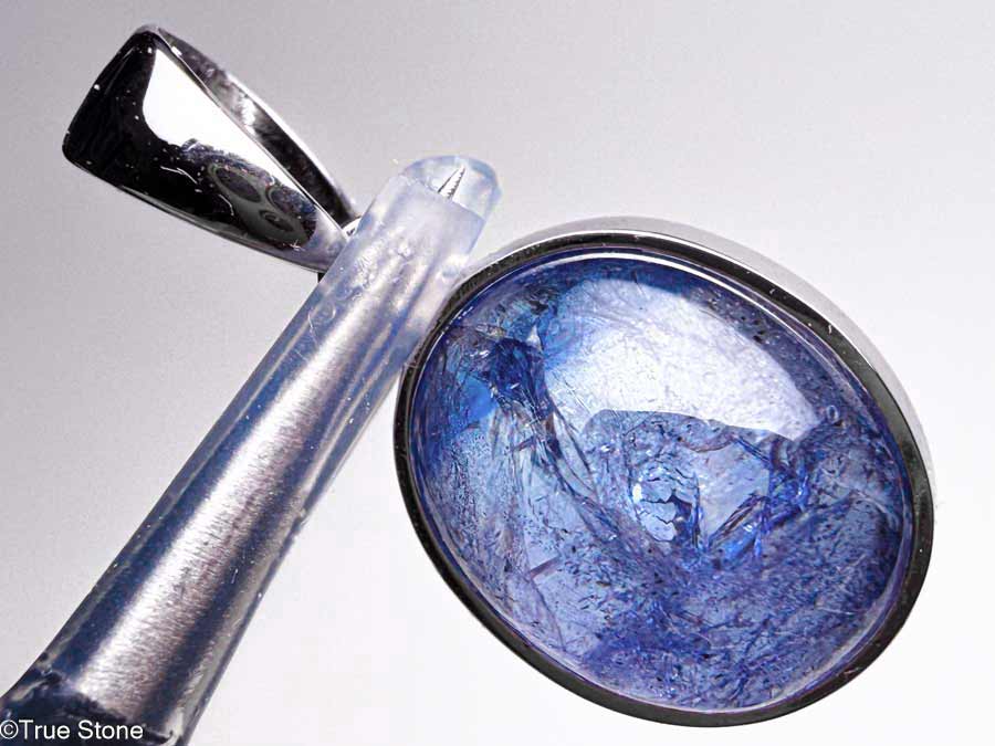 深みのある青紫色が、光の当たり方によって表情を変える一点物の天然タンザナイトペンダントトップです。 透明感のある地色の中に、天然石ならではの成長線や内部構造が見られ、人工石にはない奥行きと雰囲気をお楽しみいただけます。 カボションカットなら...