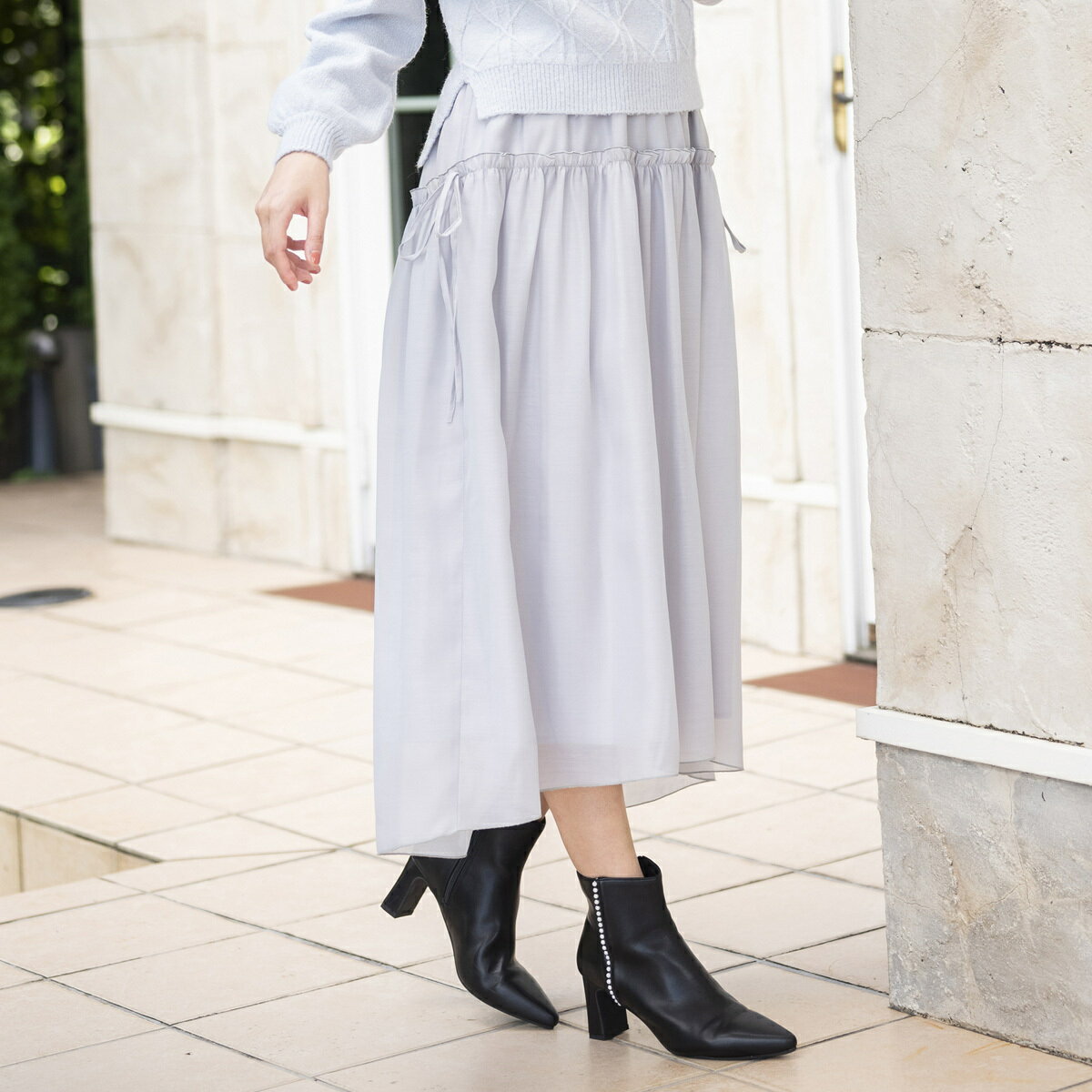 [型番:MM347218]くしゅっとしたギャザー切り替えがフェミニンなムードを高めるスカート。バックのウエストはゴム仕様なので、ラクな着心地を実現します。サイドに施されたリボンがスタイリングのアクセントに。休日のお出かけシーンに重宝したいア...