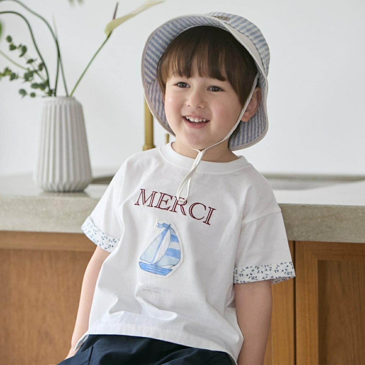 [型番：9562234]やさしいタッチで描かれた胸元のモチーフアップリケが目を引くTシャツです。フランス語でありがとうを意味する「MERCI」のロゴを刺しゅうしています。袖口に配した小花柄の生地も可愛らしいポイント。ナチュラルな色合いで着回...