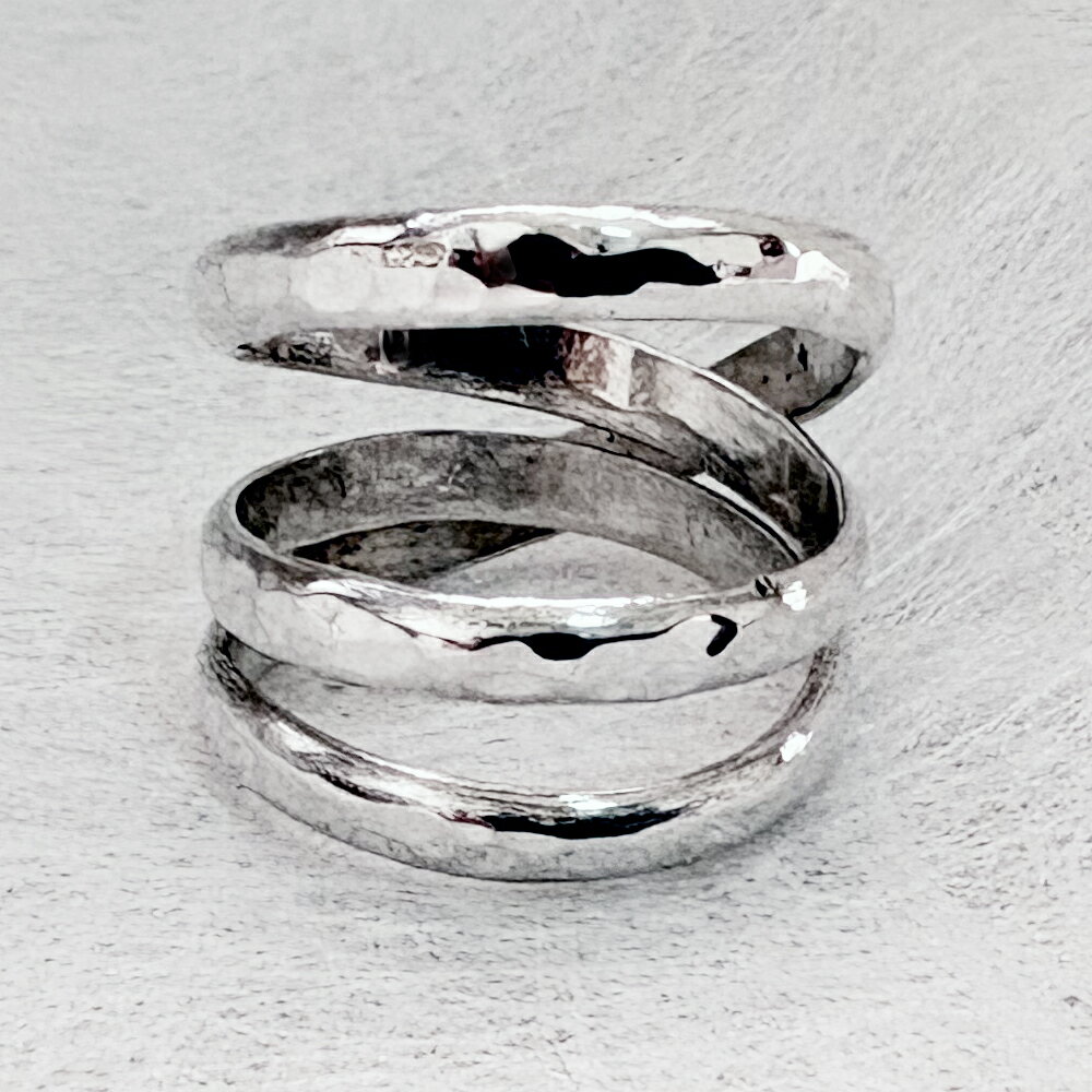 レディース ジュエリーブランド「 Elenore Jewelry ( エレノアジュエリー ) 」甲丸のシルバープレートに槌目を加え、3重巻きの輪っかにした完全ハンドメイドリング。キャストでは作れない造形の指輪です。銀線が重なり指を包み込む立...