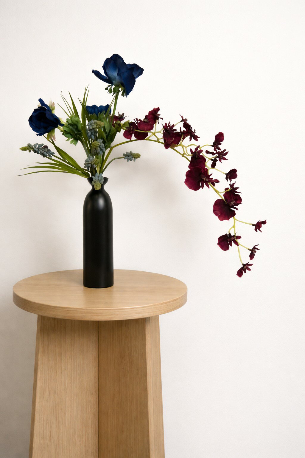 （フラワーアレンジメント＊花器セット） 深みのあるブルーとボルドーの花々が織りなす、上質でモダンなフラワーアレンジメントです。マットブラックの花器が全体を引き締め、洗練された存在感を放ちながらも、空間に自然な落ち着きをもたらします。しなやか...