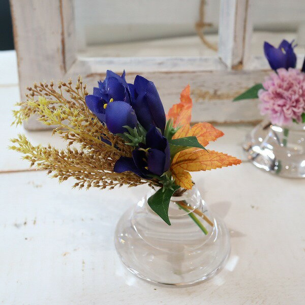 商品情報使用花材リンドウ　モミジ　オータムリーフ　他アーティフィシャルフラワー使用サイズ高さ・・・ガラス花器底面からトップの花まで　　　約10-11センチ前後ガラス花器　　　　　7．5φ5H注意点・本製品は食べ物ではありません小さなお子様が...