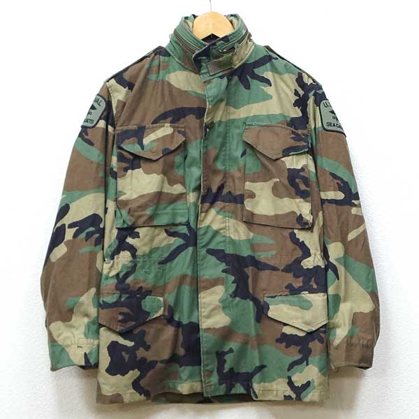 実物 米軍 M-65 フィールドジャケット ウッドランドカモ!! 最終型のYKKジッパー仕様で、ワッペン付きの本格派。 前合わせはドットボタン6個と、ジッパーの二重合わせです。 裾にはドローコード、袖はベルクロ式開度調整機能。 表記はDBA...