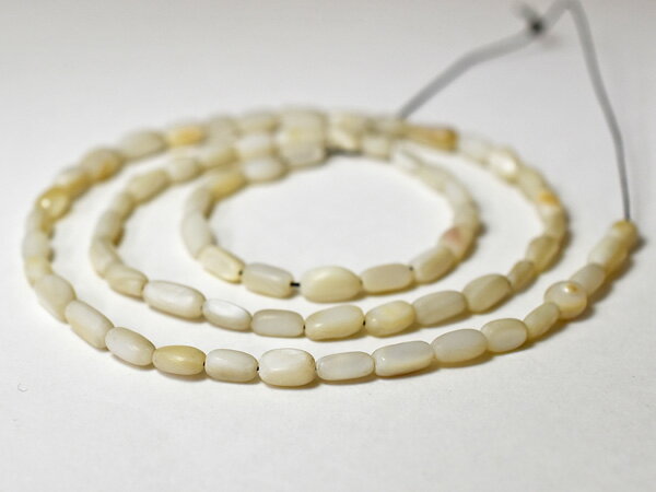 乳白色の管型の貝ビーズ一連です。多くの粒が光とビーズの角度によってキラリと光を反射して神秘的に輝きます。原産地や貝の種類等詳細は不明です。アクセサリーのパーツなどにおススメです。サイズ、形状にはやや個体差があります。写真はサンプルですが、ほ...