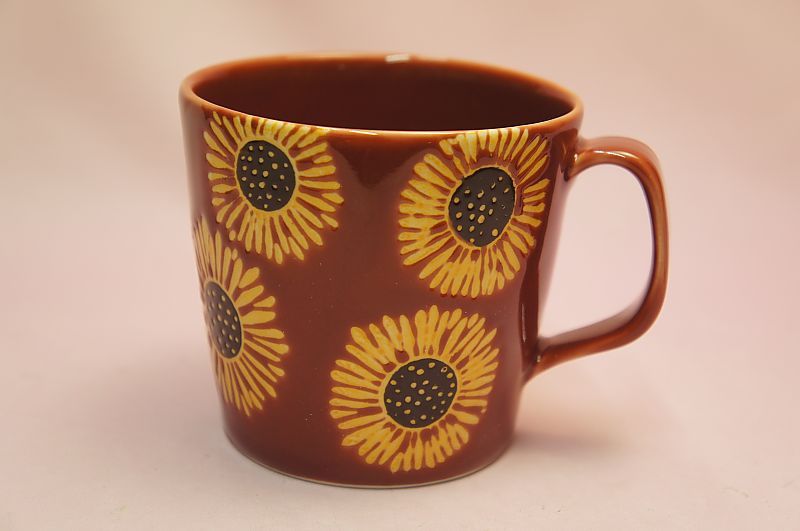 一面に描かれたヒマワリの花が可愛らしいマグカップ。地の色も、落ち着いた雰囲気の渋めの赤色になっております。安定よく、持ちやすく、口触りも滑らか。色違いで揃えて使うのも楽しいですよ。有田焼（波佐見・勲山窯、勲山製陶） 直径8．3(ハンドルまで...