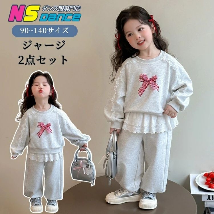ポイント リボンとレースの装飾が女の子らしさを引き立てる、スカート付きデザインのキッズ・ベビージャージセットアップ（上下2点セット）。 春・秋に活躍するスウェット素材を使用した、可愛さと動きやすさを兼ね備えたスポーツウェアです。 トップスは...
