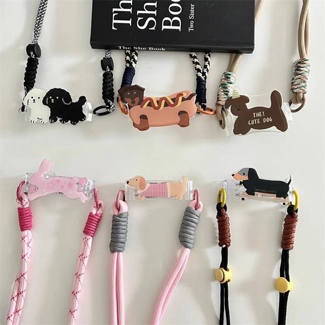 ・カテゴリ: スマホストラップ・スタイル: 男女兼用・主な素材: PVC、ポリエステル（紐）、プラスチック（バックル）・製造工程: 射出成形・バリエーション: ホットドッグホルダー＋白黒編み込み長ストラップ、ピンクダックスフンドホルダー＋ピ...