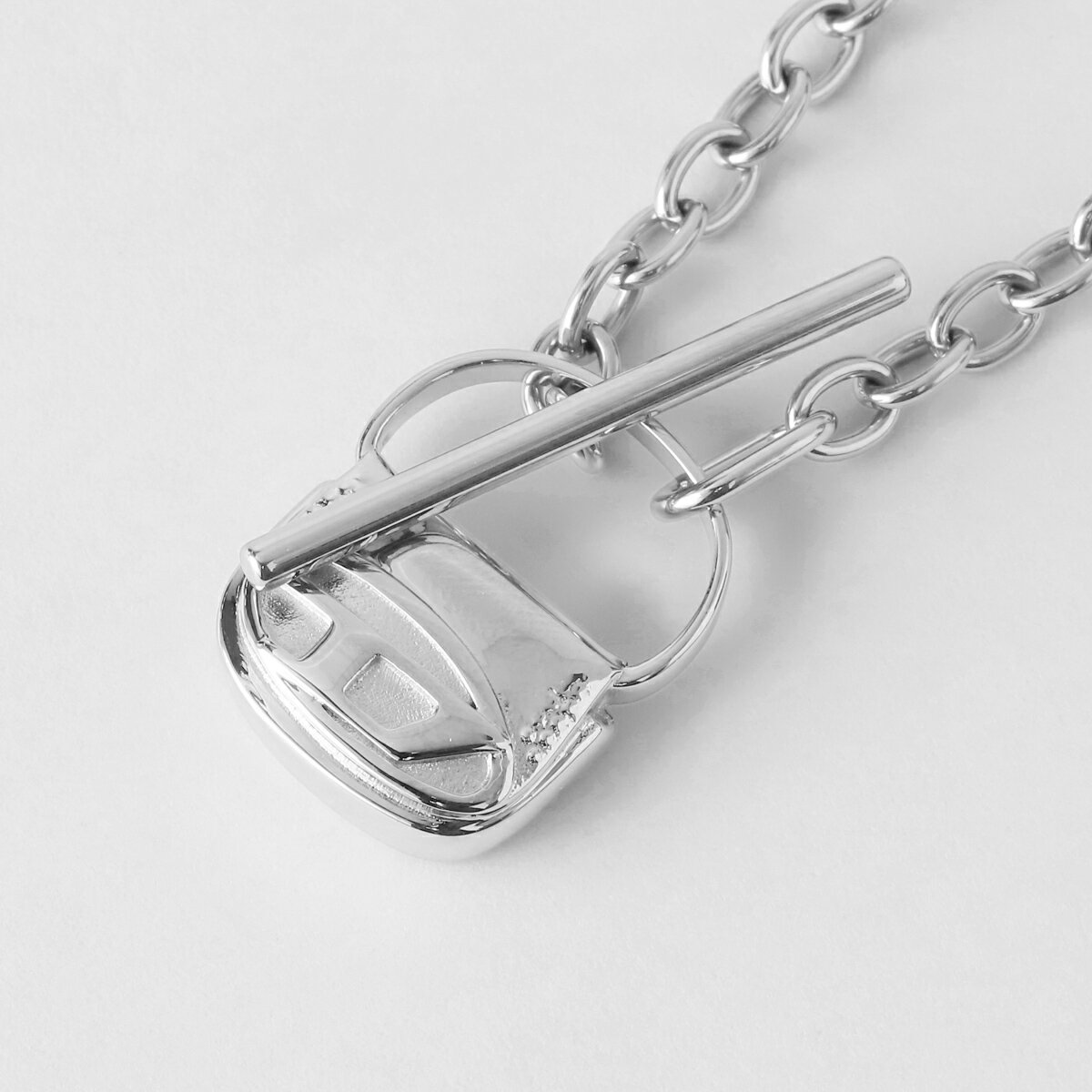 ディーゼルを象徴する1DRバッグのチャームをあしらった、存在感のあるステンレススチール製ネックレス。ミニマルなデザインながら、ブランドらしいエッジの効いたアクセントが光ります。着脱しやすいトグル式の留め具を採用し、艶のあるシルバートーンが首...