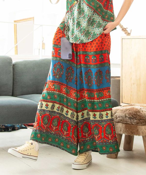 商品仕様:肌触りの良いさらりとしたレーヨン素材:のワイドパンツ。インドの日常着であるサリーの生地からインスパイアされたエスニックな柄が魅力です。アースカラーを基調にした配色で、普段のコーデにも取り入れやすいデザイン。コンパクトに持ち運べるの...