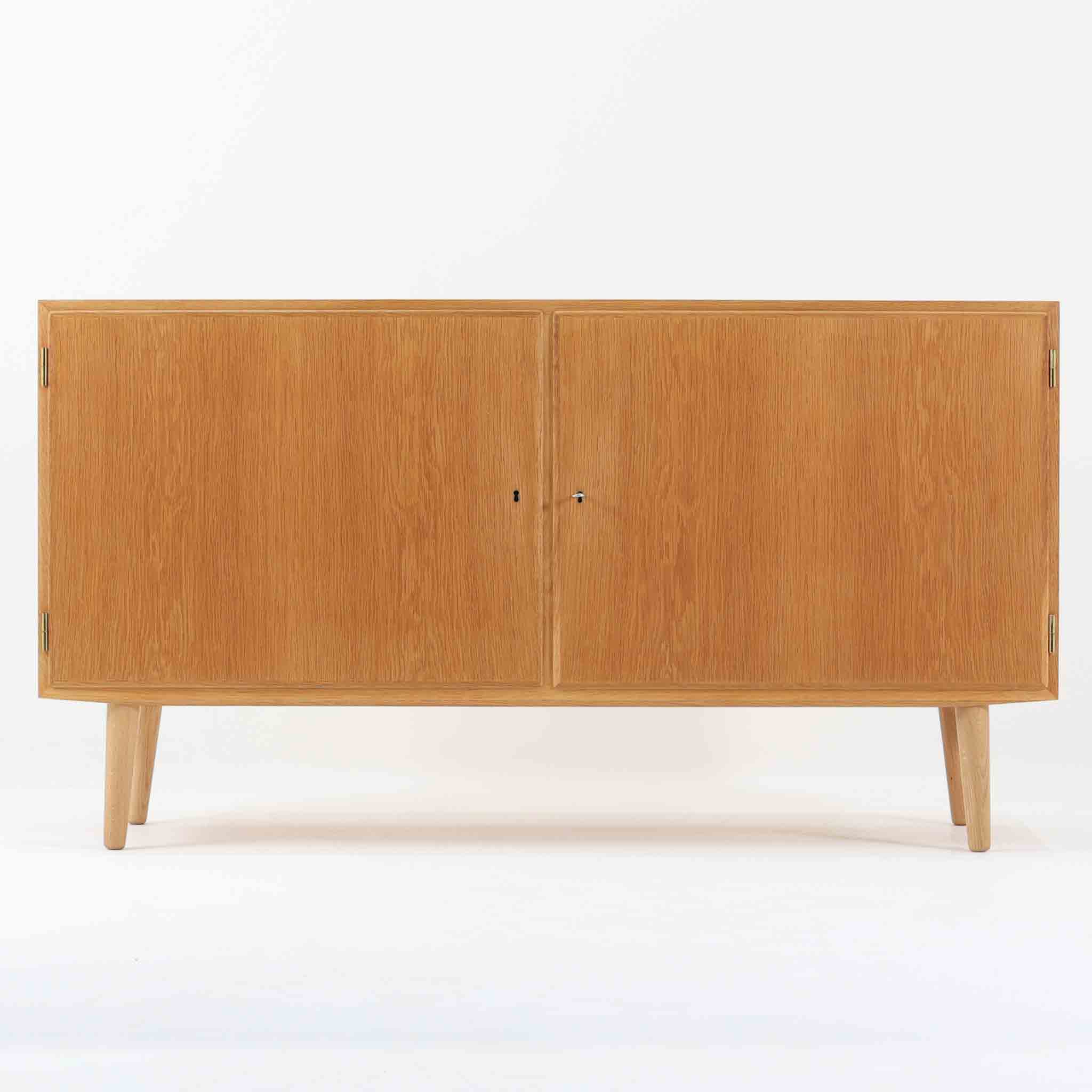 Poul Hundevadが手がけ、Hundevad & Coより製作されたキャビネットです。オーク材の端正な木目を活かしたフラットな扉構成と、細身のテーパードレッグが北欧モダンらしい軽やかさを演出します。内部は可動棚と可動式の浅型トレイを...