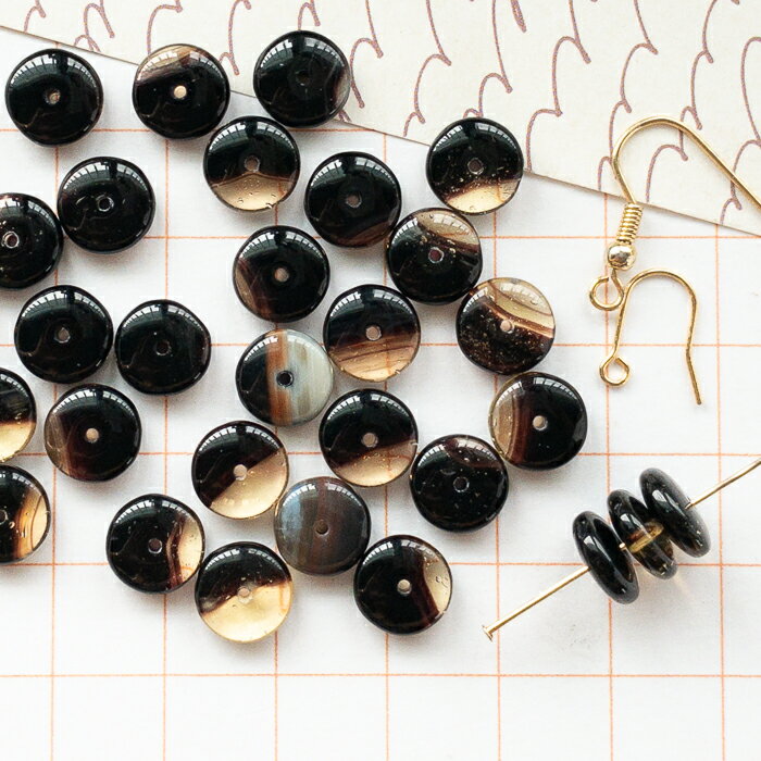 丸くて平たいスペーサービーズ。カットのないつるんとしたドーナツ型。チェコ製のガラスビーズです。 【サイズ】 9ミリ　厚み3.5mm (画像のマス目は1センチ四方です) 【個数】 28個 【色味】黒に近いパープルにクリアブラウン、ミルキーホワ...