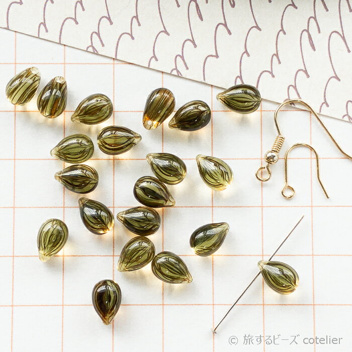 コロンとしたシルエットの可愛らしいドロップビーズ。チェコ製のガラスビーズです。 【サイズ】 6 × 9ミリ (画像のマス目は1センチ四方です) 【個数】 18個 【色味】クリアライトグリーンに不透明ブラウンのストライプ。 【色違い】cote...