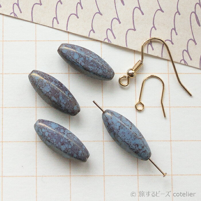 6面のロングオリーブ型プレスビーズ。チェコ製のガラスビーズです。 【サイズ】 7x19ミリ (画像のマス目は1センチ四方です) 【個数】2個 【色味】不透明ブルーにまだら感のあるブロンズ系コーティング 【色違い 一覧】cotelier-lo...
