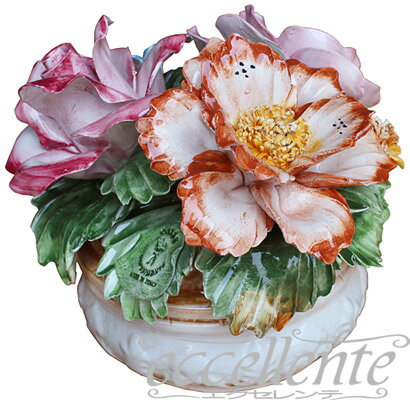 イタリアの伝統工芸が息づく、陶器製のエレガントなフラワーアレンジメント。優美なバラの花々が立体的に咲き誇り、繊細な花びらの重なりやグラデーションまで丁寧に表現されています。アンティーク調の台座は、曲線美あふれる装飾が施され、イタリアならでは...