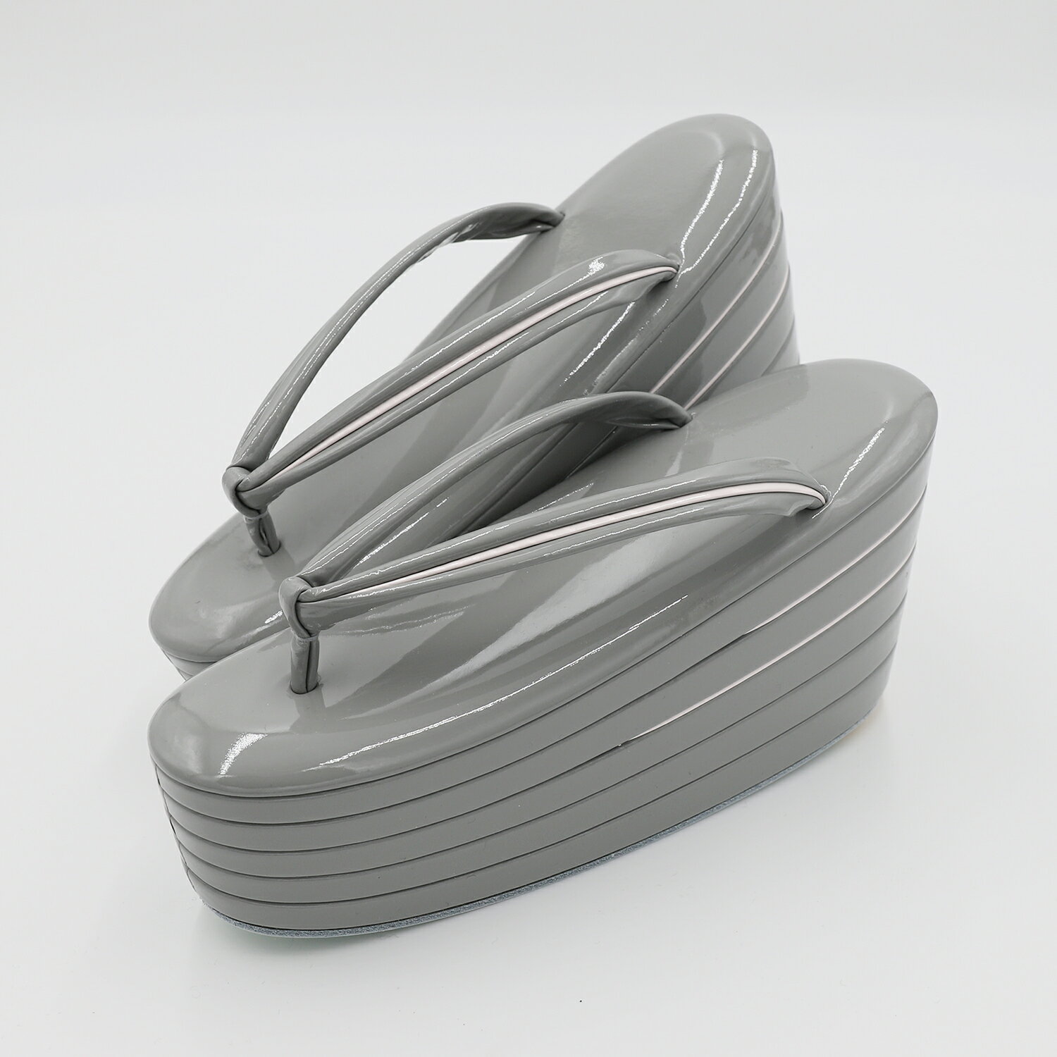 アゲ草履® 5分5枚芯 エナメル グレー×桜色 熟練の職人が手作業で仕上げた本革草履です。形を整えたコルクの芯に牛革を巻き、5段に重ねた、かかとの高さ9cmのハイヒール草履です。 絶妙な傾斜角度、脚長効果にスタイルアップでテンションが高まり...