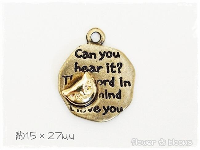 ネコの顔と英字が書かれたラウンドパーツが組み合わさったチャームです(*´∀｀*)カラー：真鍮古美＋ゴールド（ネコ部分）＜ネコ顔部分＞　━ K16ゴールドコーティング（鍍金）━　※ 純金を使用することにより、従来のゴールドより、変色しにくくな...