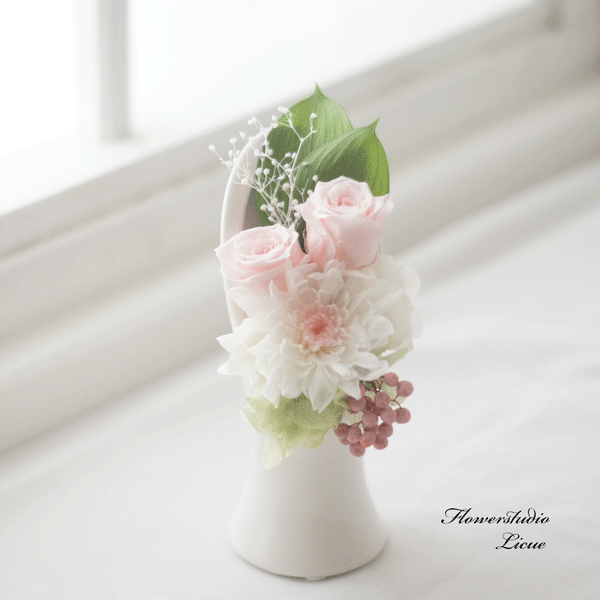 商品情報使用花材◎プリザーブドフラワー　ことね菊、バラ、紫陽花、カスミソウ、ペッパーベリー、ルスカス◎花器　ツヤのある白の陶器サイズ高さ約15センチメートル横約7センチメートル奥行約8センチメートルラッピングクリアボックスに黒いリボンをお掛...