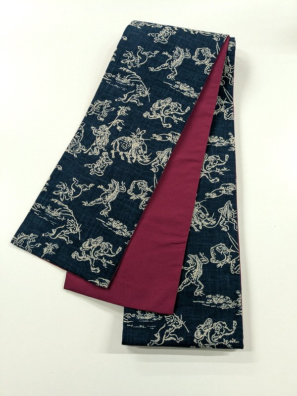 商品説明：大人気の鳥獣戯画模様の福服特製にて制作 紺色地に鳥獣戯画×赤紫無地 サイズ：幅約16、長さ約399cm 素材：綿 新品 TPO：小紋や紬、 浴衣等 ※帯のみの販売となります ※柄行は画像を違う場合もございます。