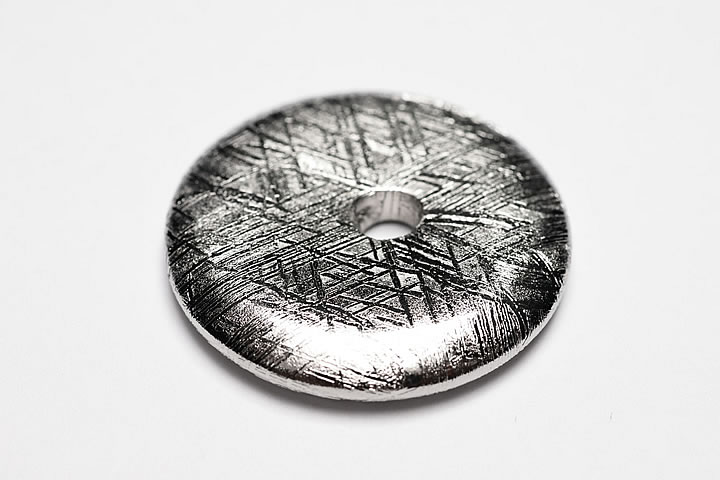 2.7×2.7×0.4cm 穴サイズ:約4mm 綺麗な格子模様が出ているギベオンのドーナツです。かなり大き目の穴が空いておりますので、革ヒモなどに通してペンダントトップとしてお使いいただけます。 表面は錆びにくいようにロジウムでコーティング...