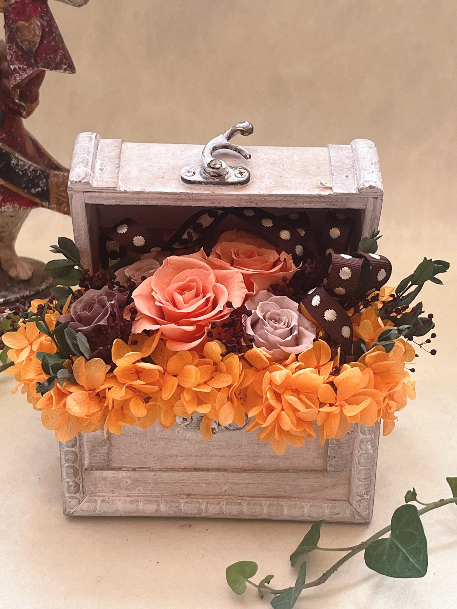 オレンジ色とブラウンのバラが絶妙に組み合わさり、華やかさとシックさを兼ね備えたアレンジメントです。 ブラウンの水玉リボンがアクセントとなり、お洒落感をさらに引き立てます。白いアンティーク箱のアレンジは、お誕生日や結婚祝い、母の日、敬老の日な...