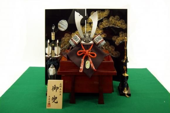 展示品激安大特価 10号いぶし銀兜飾り 間口55cm　奥行き35cm　高さ48cm 展示品です。 10号いぶし銀兜飾り。銀小札に正絹朱糸縅で仕立て上げております。コンパクトながらも忍び緒も太くボリュームが有ります。おびょう風は黒ピアノ塗りに...