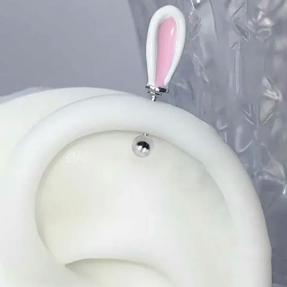 エナメルコーティングで白色とピンクに彩られたリアルなウサギの耳をストレートバーベル型のボディピアスにセットした可愛いピアス。ユニークで可愛いデザインが魅力のファッションピアスです。立体感のあるウサギの耳は、遊び心たっぷり！どんなスタイルにも...