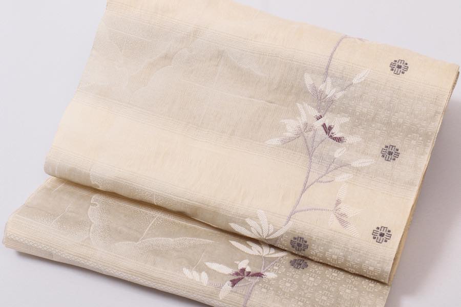 西陣の単衣 盛夏の夏帯　名古屋帯になります。 横段に染分けのようになっていて 地紋には雪輪右側にお花がある素敵な図案の織になてます。 単衣の6月から9月上旬ごろまで使っていただけます。 単衣の軽めな付下げ、小紋、無地、紬、夏の軽めな付下げ、...