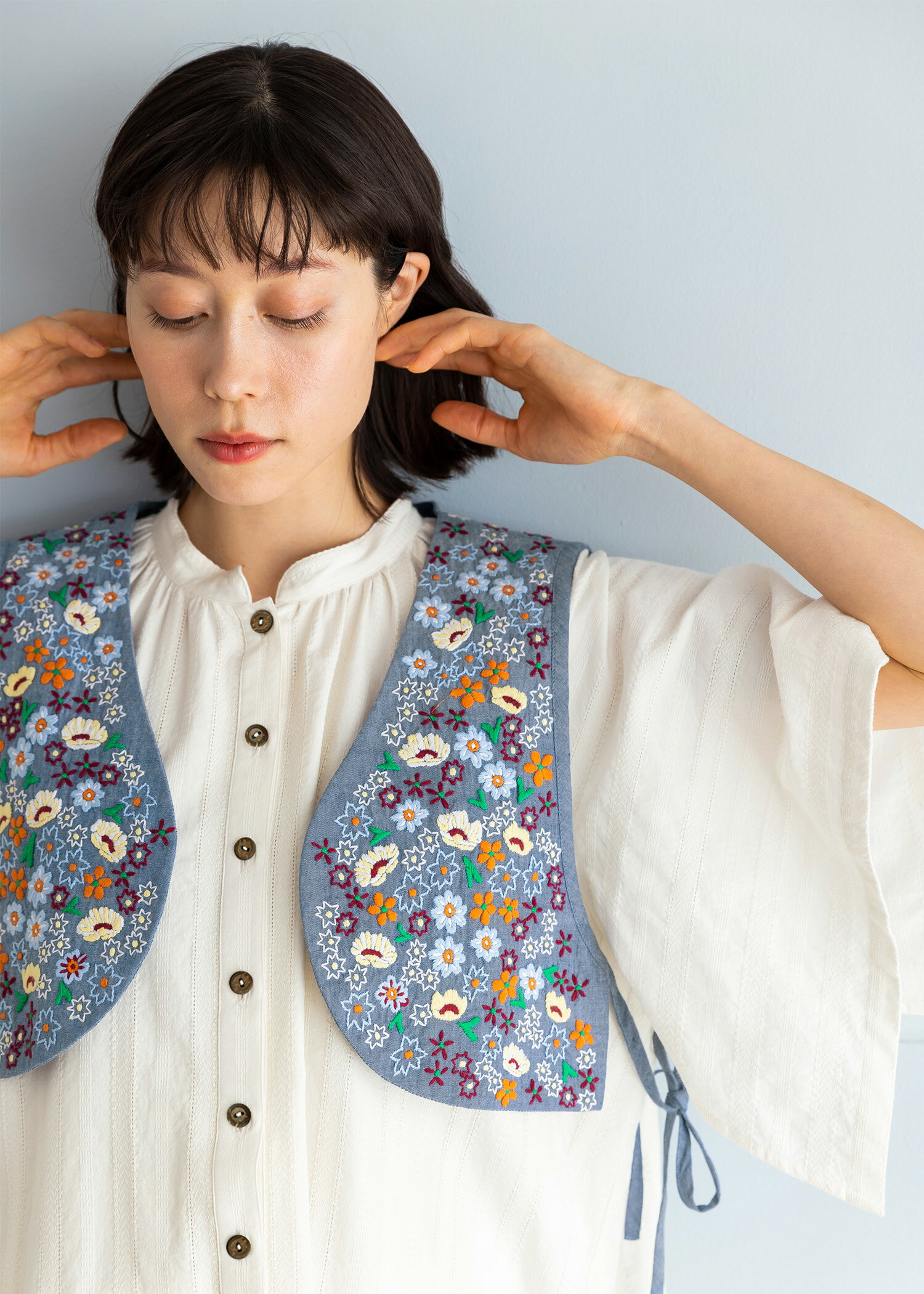 手織りのコットンシャンブレー生地にカラフルな手刺繍をほどこした、手仕事の魅力を存分に味わえるシリーズです。全面に手刺繍が入った、贅沢なショート丈のベストです。脇はひも結びなので軽く羽織れて、袖にボリュームのあるアイテムにも合わせることができ...