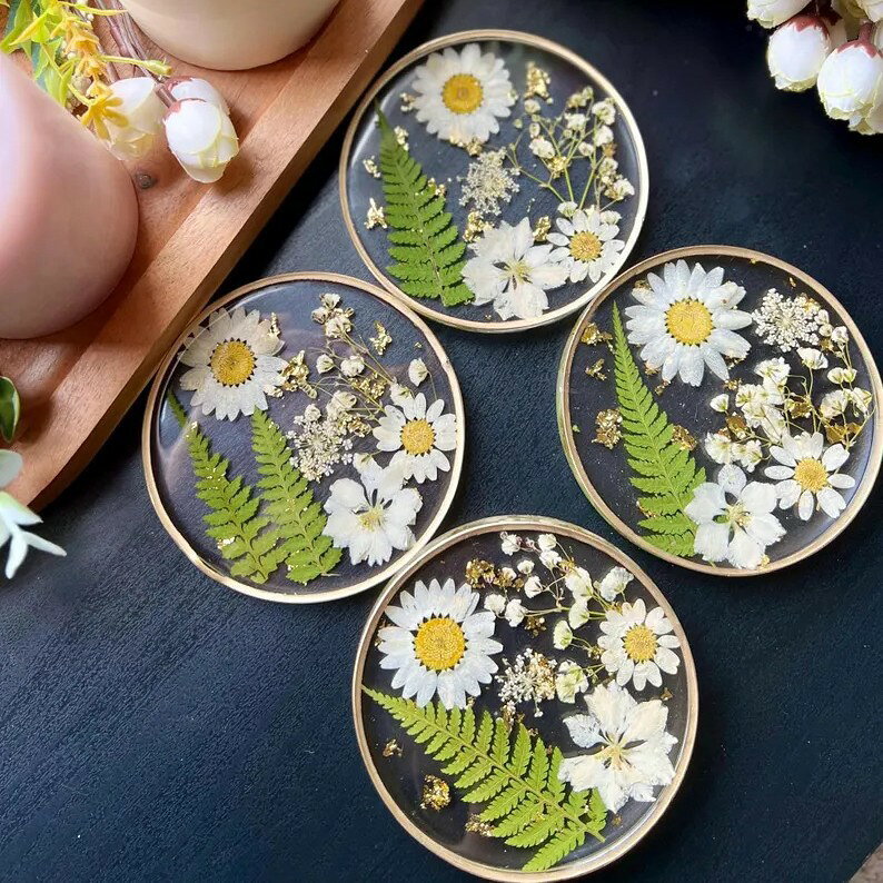 製品説明： デイジー樹脂コースターで、ご自宅に自然な美しさを添えましょう。透明度の高い樹脂と高品質のドライフラワーを使用し、洗練された北欧スタイルでどんなお部屋にもぴったりです。素朴なデイジーティーマットは、美しいだけでなく実用的で、断熱性...