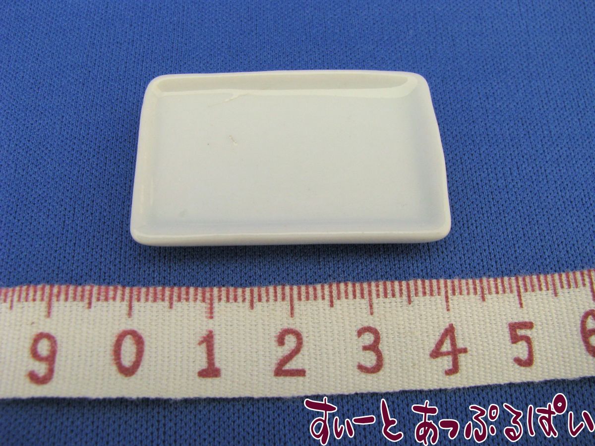 陶器のトレイです。ミニチュアフードを乗せたり、お店屋さんのディスプレイに使ったり、ドールハウスの様々なシーンでお役立てください！サイズ：39x25ミリ（取っ手の部分含まず）、高さ約4ミリ。