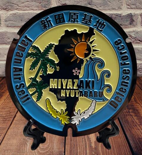 新田原基地エンブレムをモチーフにしたデザイン。 サイズ：径90×厚5mm 材　質：亜鉛合金