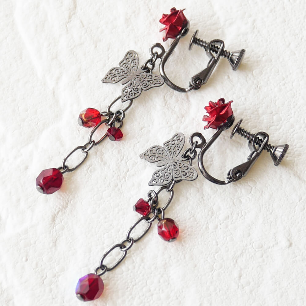 【ローズガーデン シリーズ】 レッドローズ×ガンメタのゴステイストなイヤリング 赤い薔薇と繊細なステンド蝶の下で オーロラ加工のレッドビーズ3個が揺れる 蝶＆ローズシリーズの再製作しました！ ガンメタ仕上げ 【サイズ】 　全長　縦：約4.8...