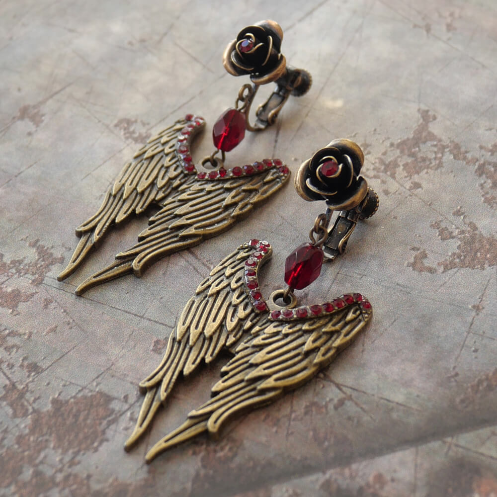 【ティアーズヘブン オリジナル】 薔薇の中央とメタルの翼パーツにあしらわれたレッドストーンが特徴のイヤリングです。 他とは被らない個性的なデザインが魅力で、特別なシーンでのアクセントとして最適です。 薔薇と翼のモチーフが繊細に組み合わさり、...