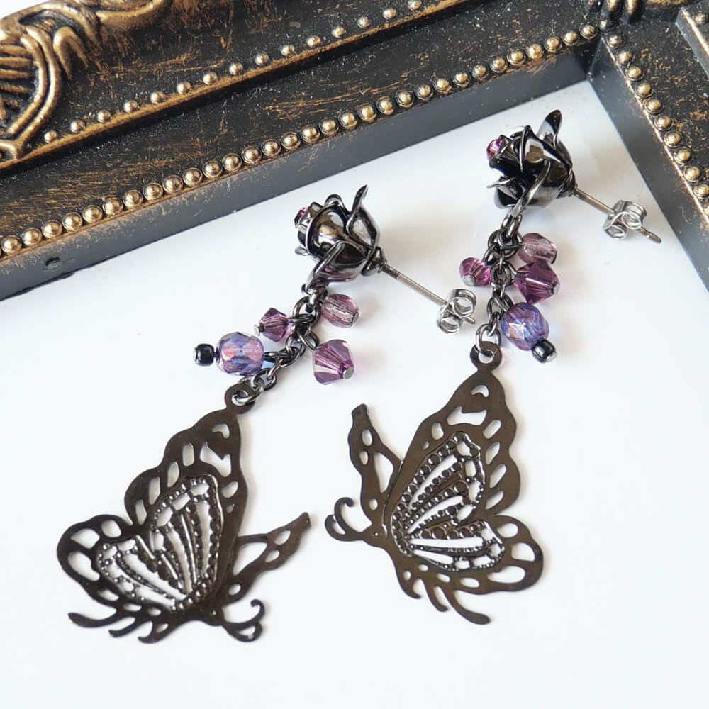 【ティアーズヘブンオリジナル】 紫の薔薇と蝶が織りなす美しいデザインのピアス パープルストーンが薔薇のスタッドピアスのヘッドに輝き、エレガントな印象を与えます。 羽ばたく蝶のデザインは、左右で異なるステンド蝶のパーツを使用しており、動きのあ...