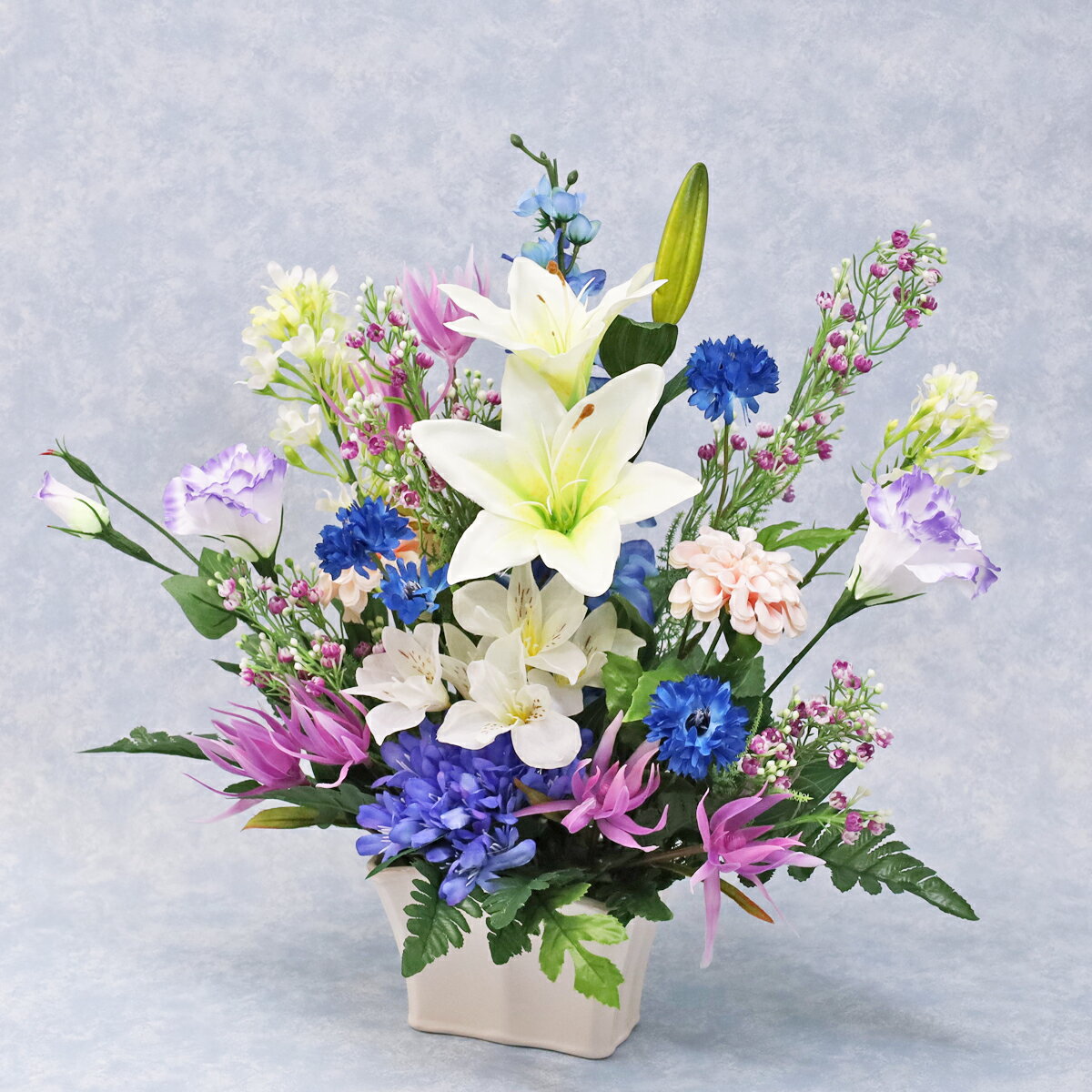 大振りな花弁が華やかなすかし百合の、お供えのフラワーアレンジです。 サイズ：約高さ48×幅48×奥行28cm＊商品の仕様は変更になる場合がございます＊受注制作のため数日お時間をいただく場合がございます シルクフラワーとは、シルクの様な光沢の...