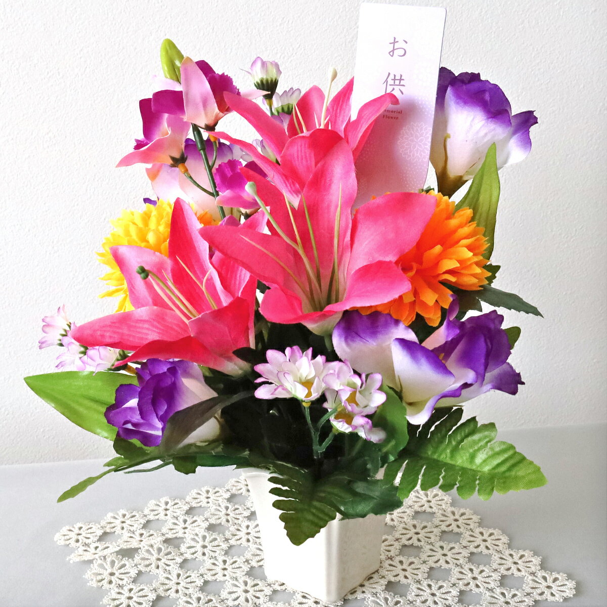 当店の人気仏花 「デンファレとユリの花束」と同花材で仕立てたアレンジです。お墓とお仏壇、それぞれの場所にぴったりな形で飾っていただける、新しいお供え花のスタイルです。コンパクトなスペースにもそのまま置いて飾れます。 ビビッドカラーのユリをメ...