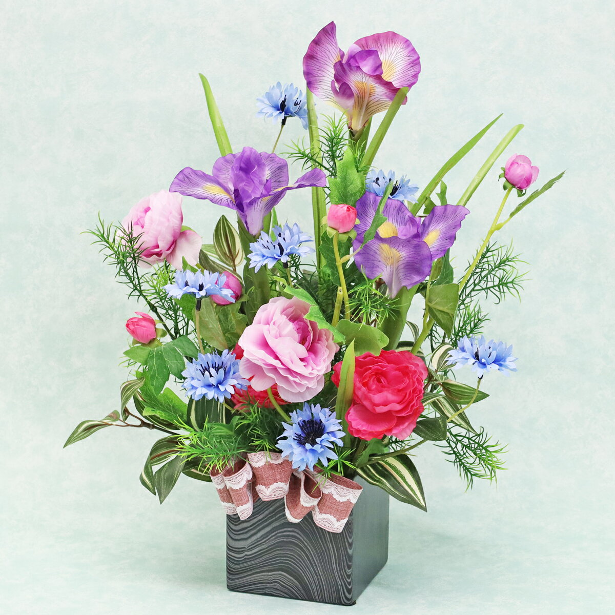 紫、青、ピンクの花々とシックな黒い器の組み合わせが魅力的なアレンジです。サイズ：約高さ44cm×幅32cm×奥行24cm＊商品の仕様は変更になる場合がございます＊受注制作のため数日お時間をいただく場合がございます シルクフラワーとは、シルク...